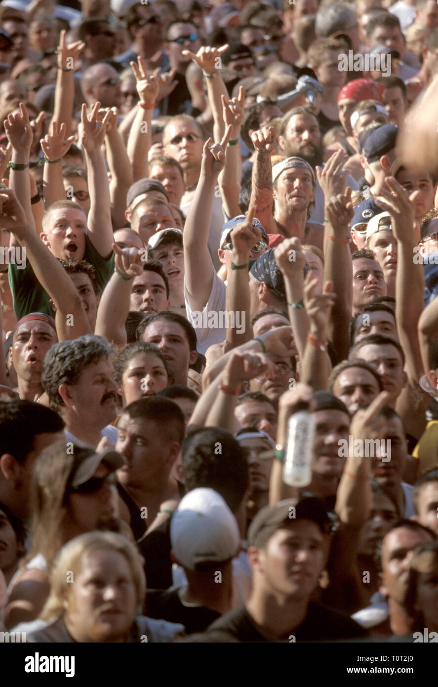 Concert fans are shown with their arms raised over their heads during ...