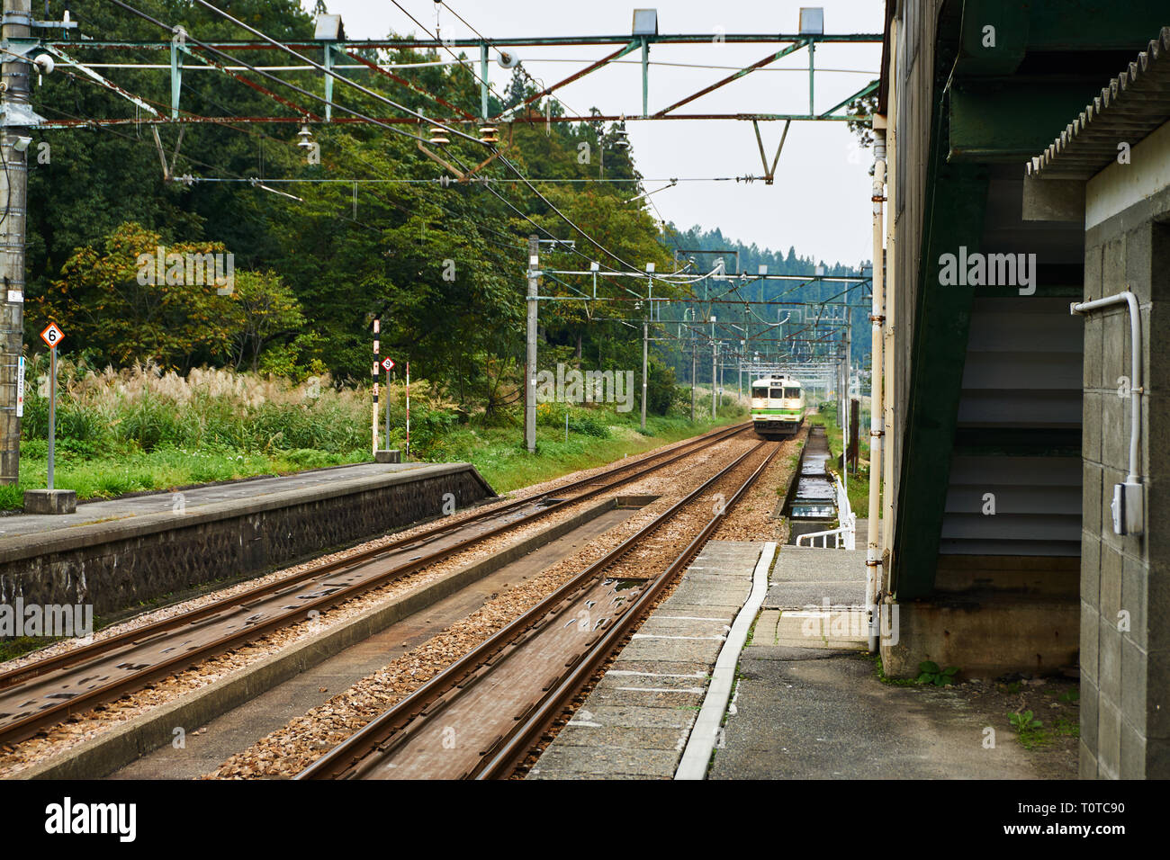 A small train approaches a countryside train station on the JR Joetsu ...