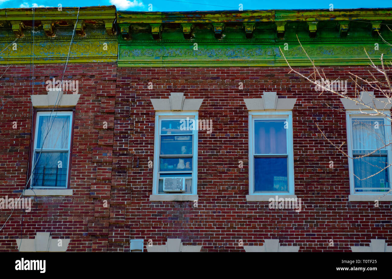 Brick apartment building with window AC and toys inside the window ...