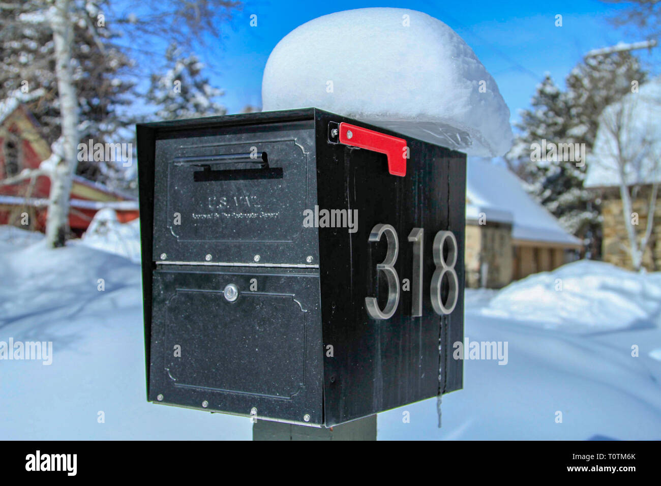 Modern mailbox with snow precariously hanging off the top during the ...