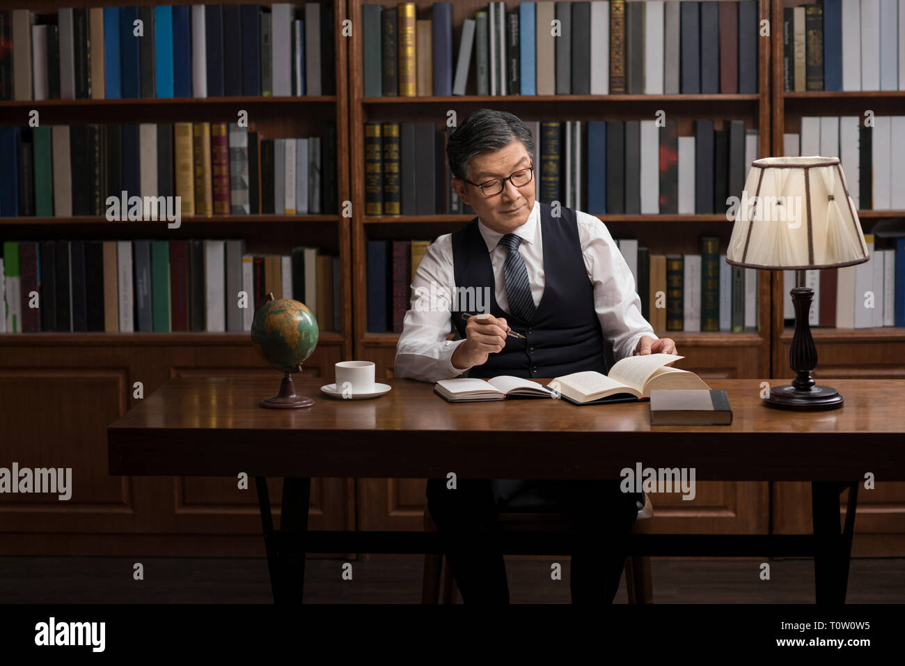 Senior businessman reading book in study Stock Photo - Alamy