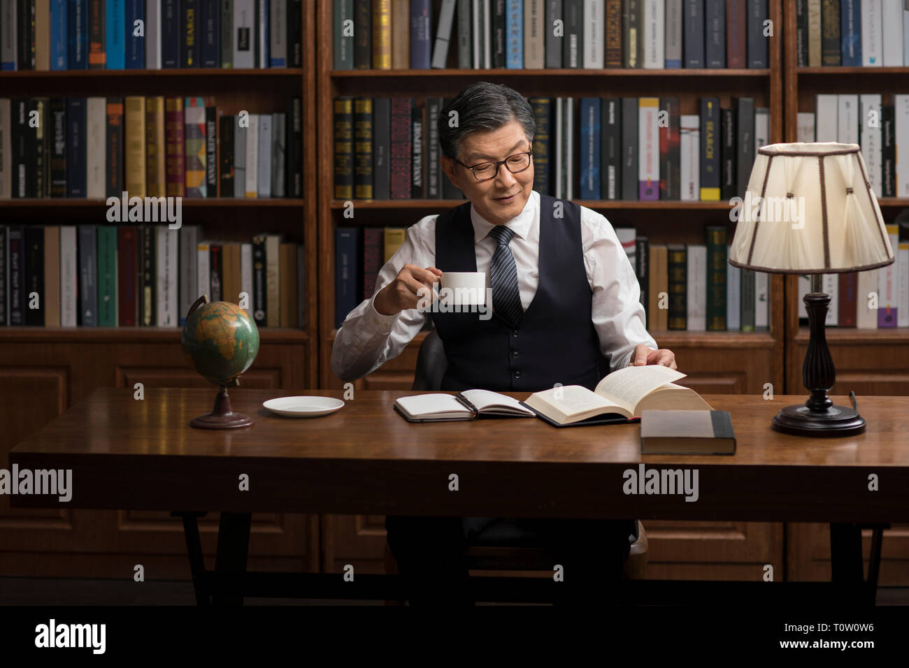 Senior businessman reading book in study Stock Photo - Alamy