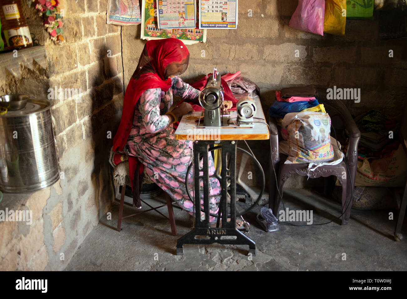 A woman making clothes using an old-fashioned sewing machine. Kakani ...
