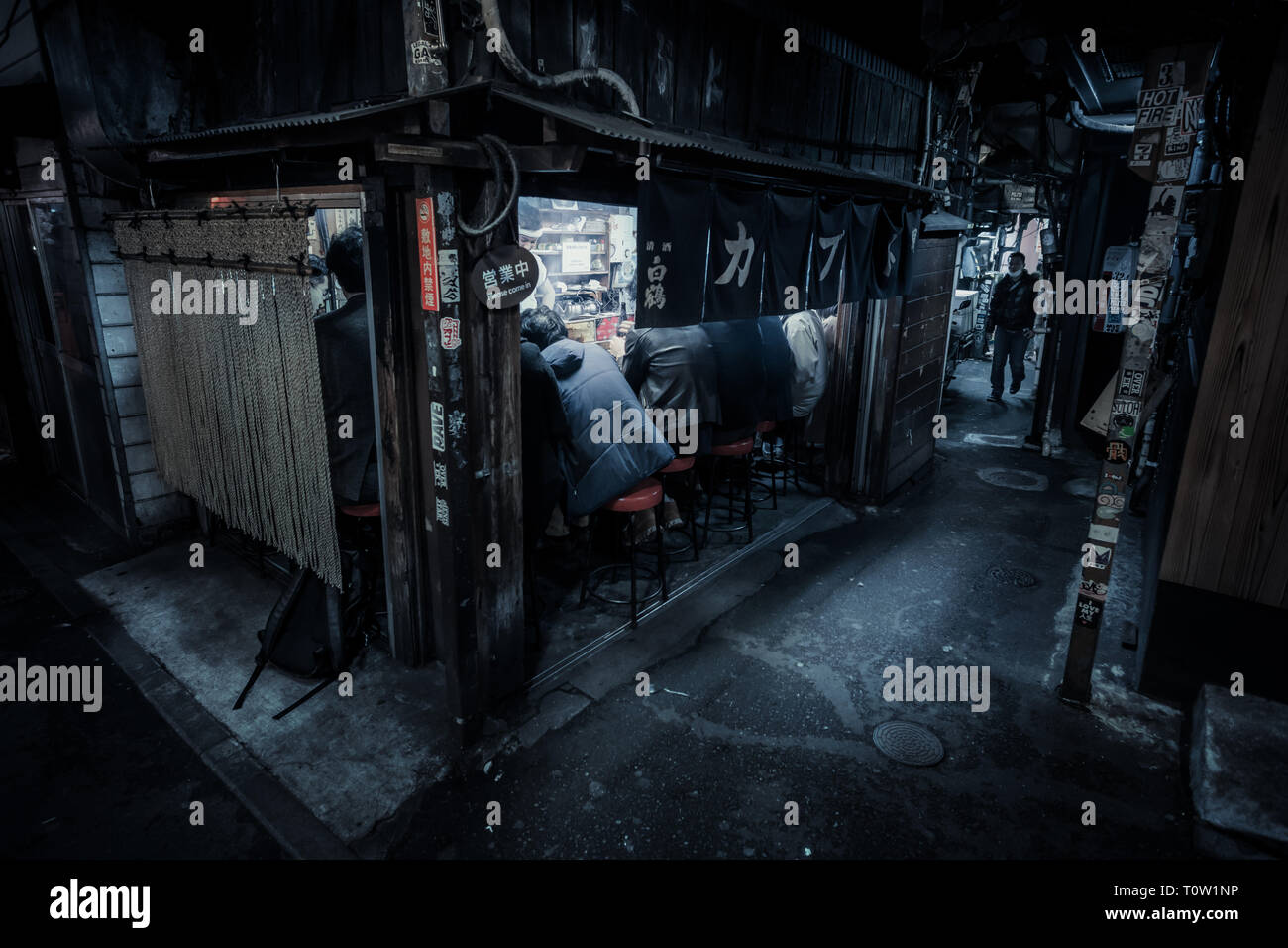 Evening in Omoide Yokocho, Shinjuku, Tokyo. Customers sit at a run down ...