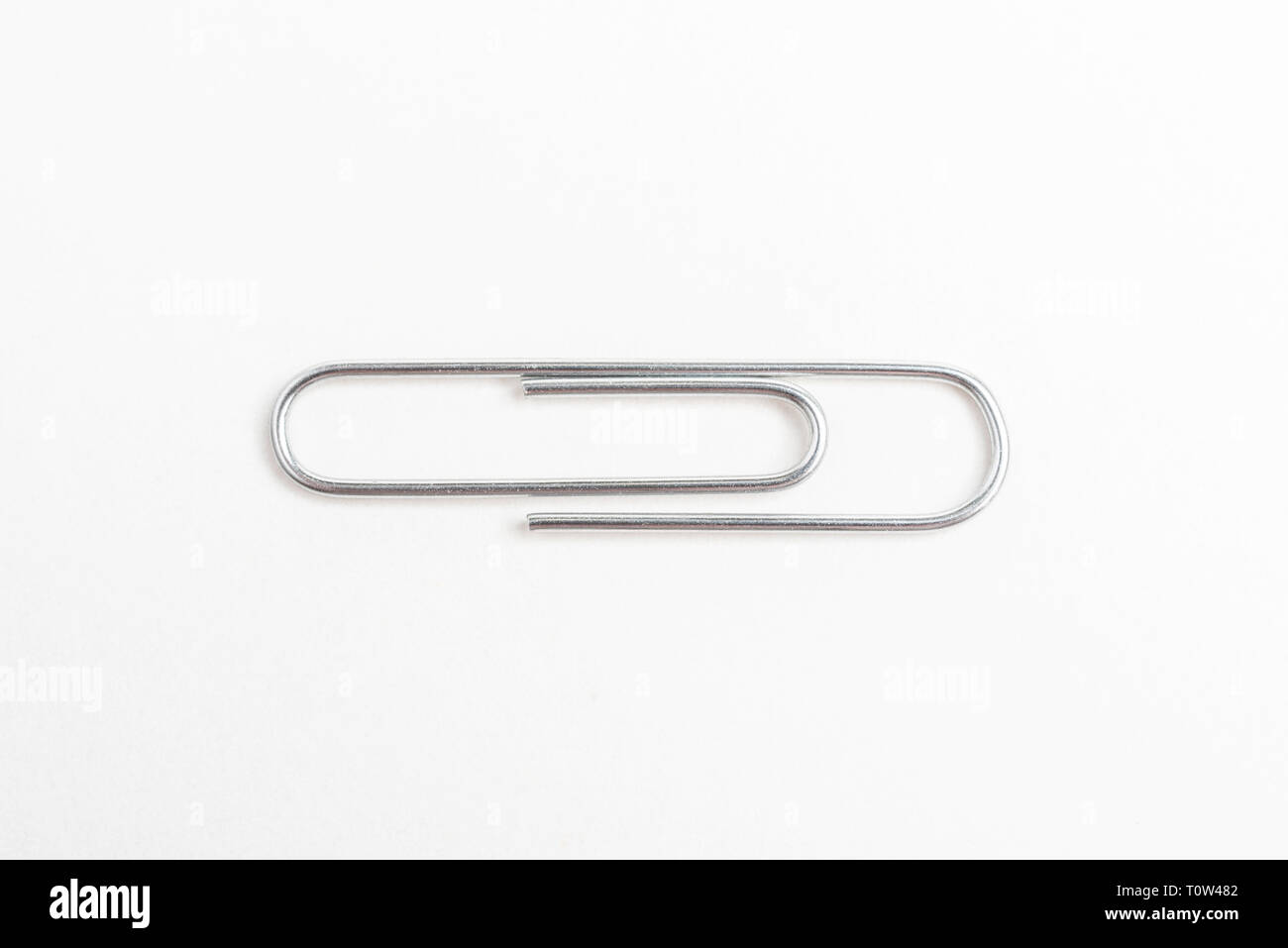 A macro shot of a metal paper clip set on a plain white background ...