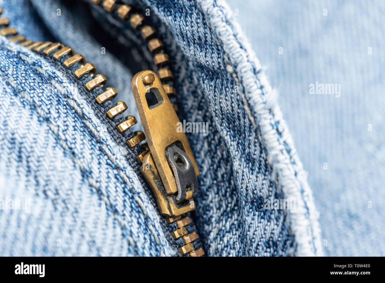An extreme close-up or a macro shot of a half-open denim jeans zipper ...