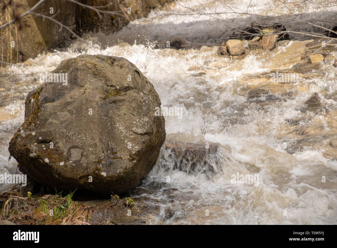 Mountain river flowing by large rock Stock Photo - Alamy
