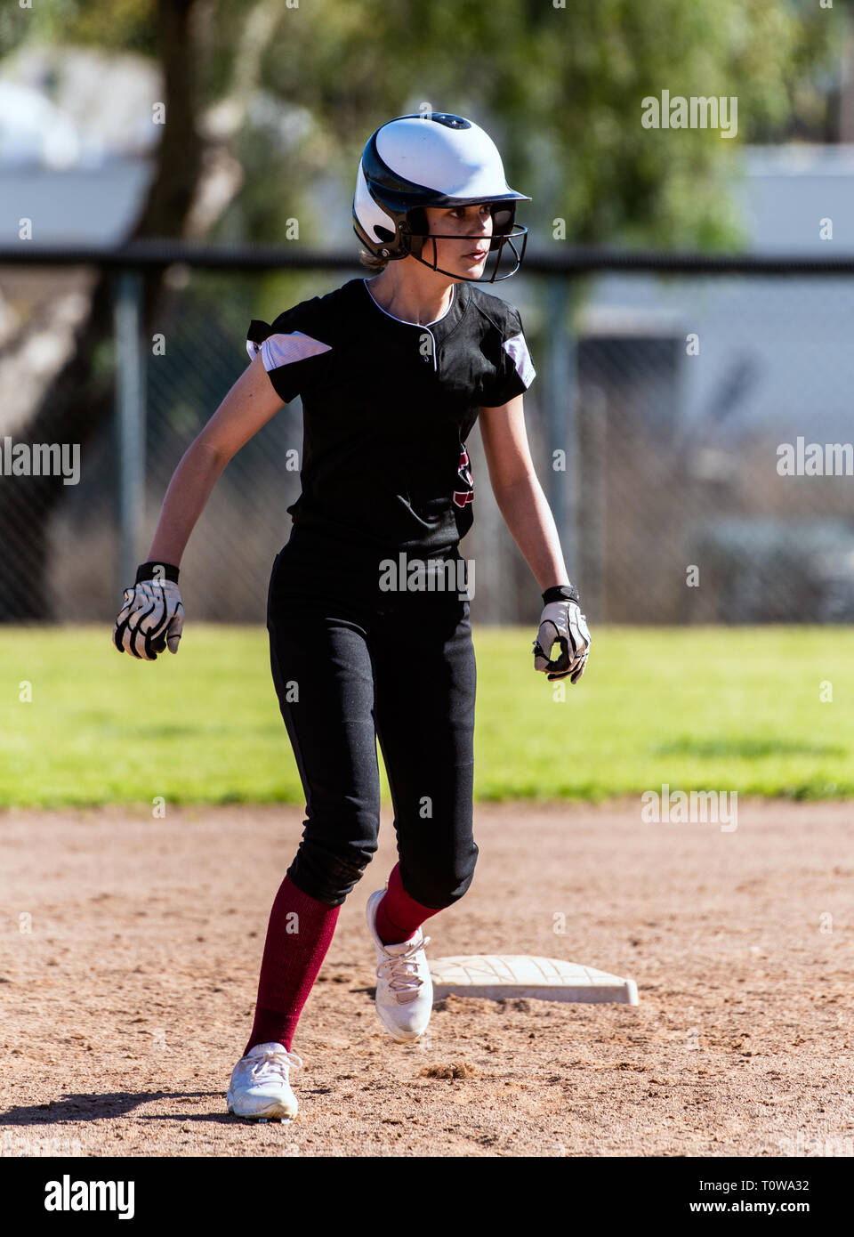 Female softball player in black uniform taking an agressive lead off ...