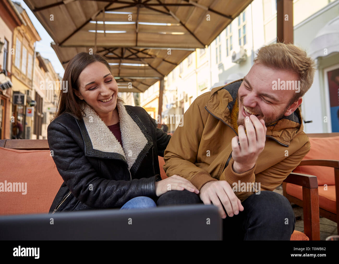 two people, 20 - 29 years old, candid laughing out loud. sitting in a ...