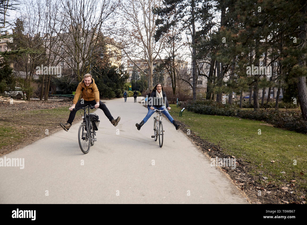 two young people, 20-29 years old, riding a bicycle in a park with legs ...
