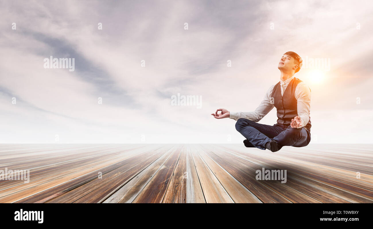 Businessman in lotus pose. Mixed media Stock Photo - Alamy