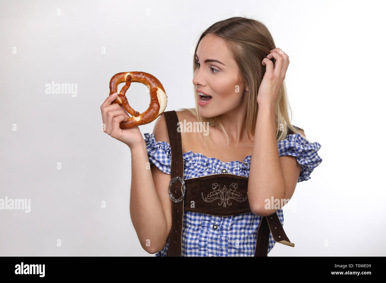 Pretty Oktoberfest woman with blue white dirndl holds a pretzel Stock ...