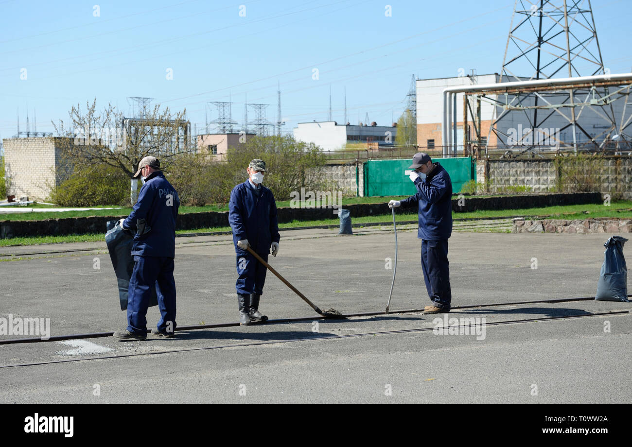 Workers in protective clothes decontaminating square near building of ...