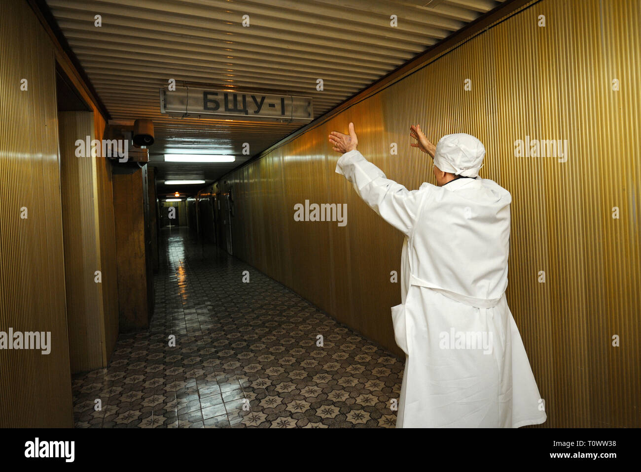 Workers in protective clothes going down the passageway of the ...