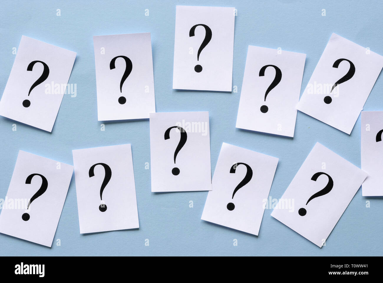 Irregular rows of printed question marks on white cards or signs ...