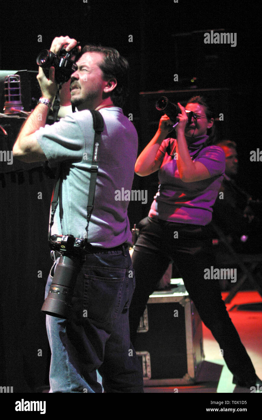 Concert photographers are shown recording still photographs during a ...