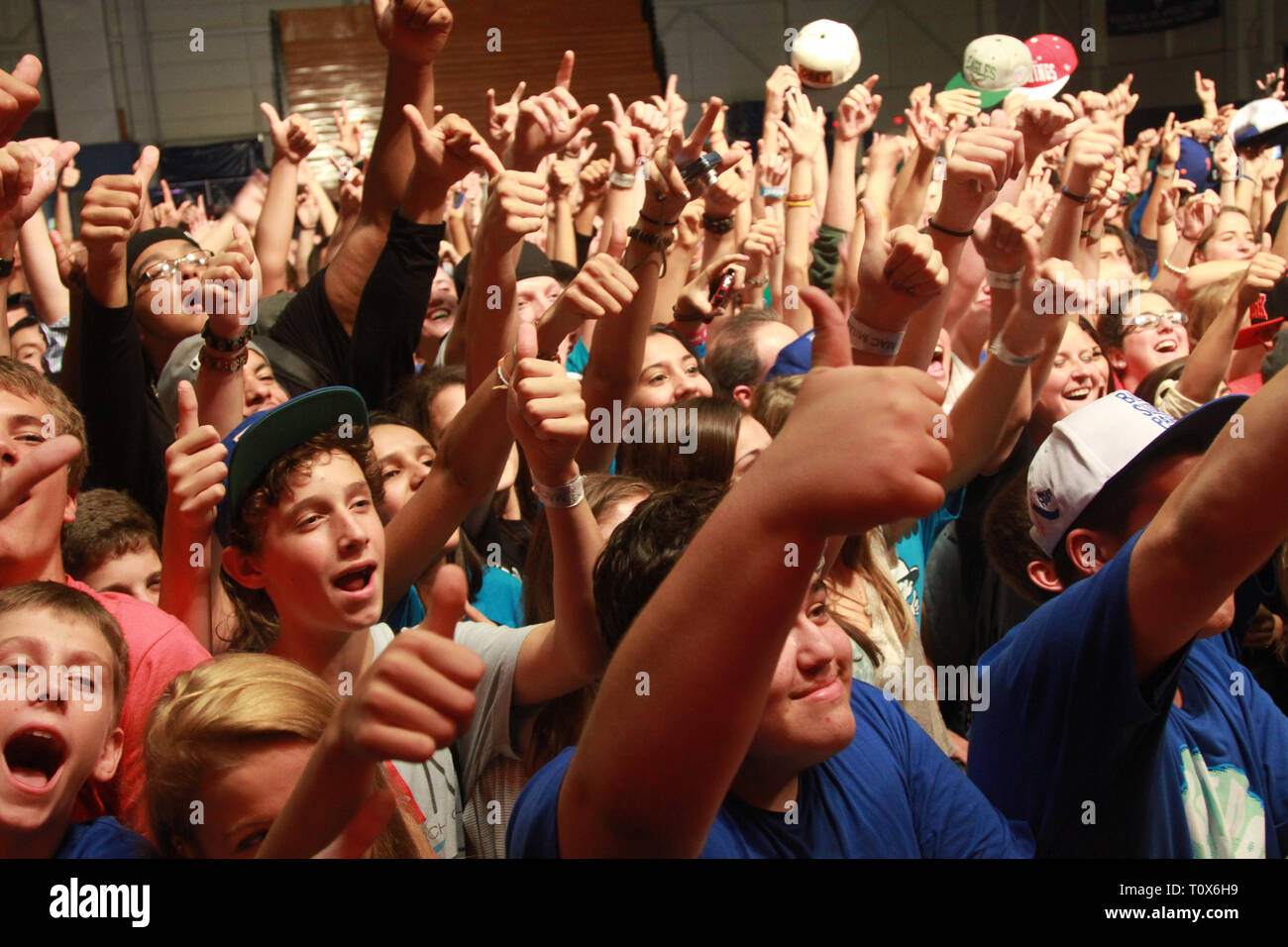 Teenage concert fans are shown with their arms raised overhead during a ...