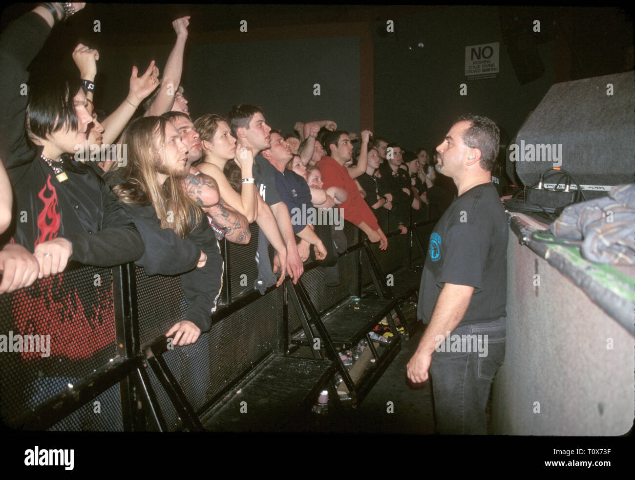 Front row concert fans are shown lined up against the stage barricade ...