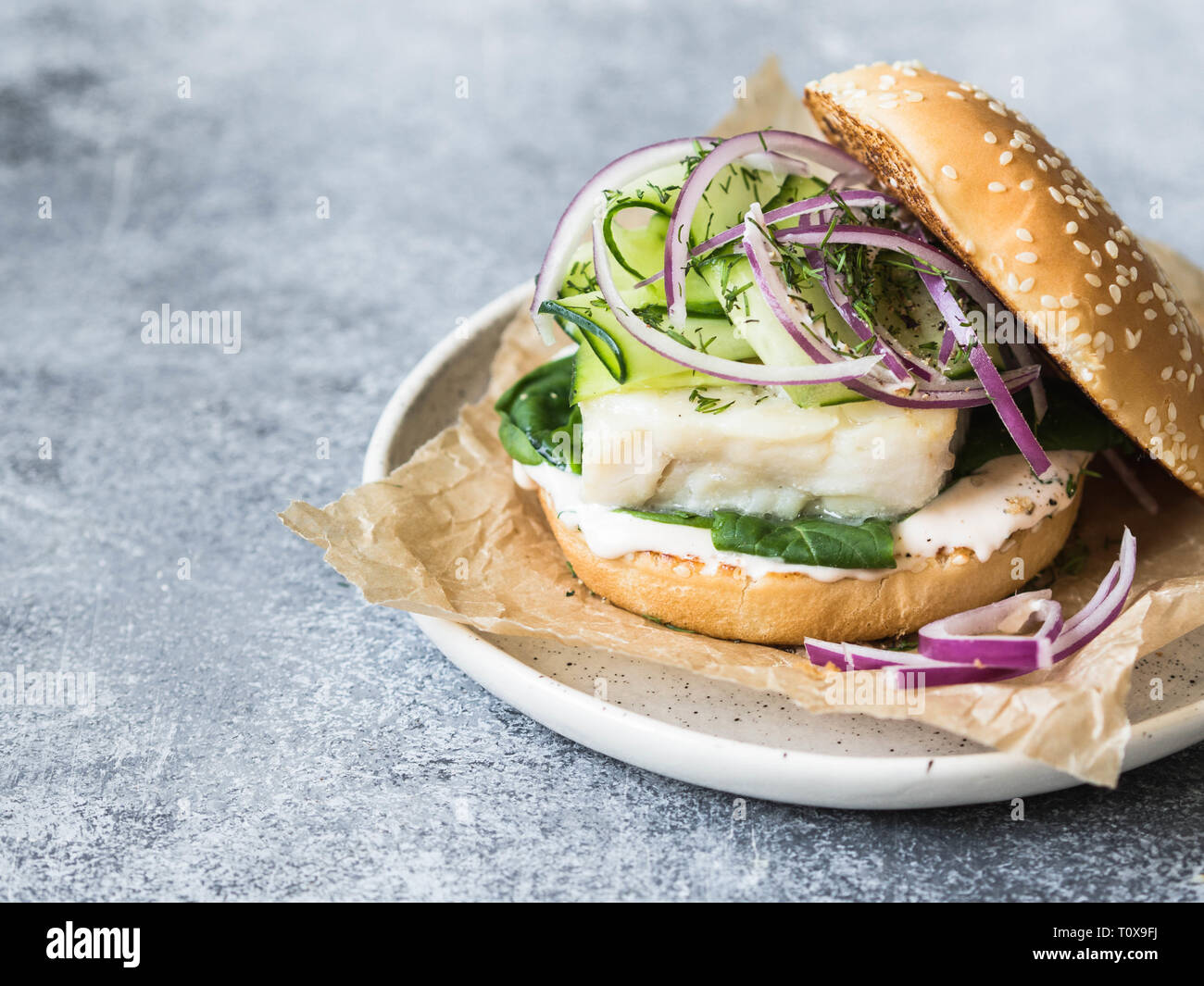 Homemade fish burger of white fish fillet with cucumber slice, red ...