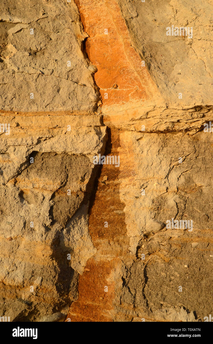 Cracked surface of a clay slope. The cracks have allowed access of oxygen, so the ferrous soil ...
