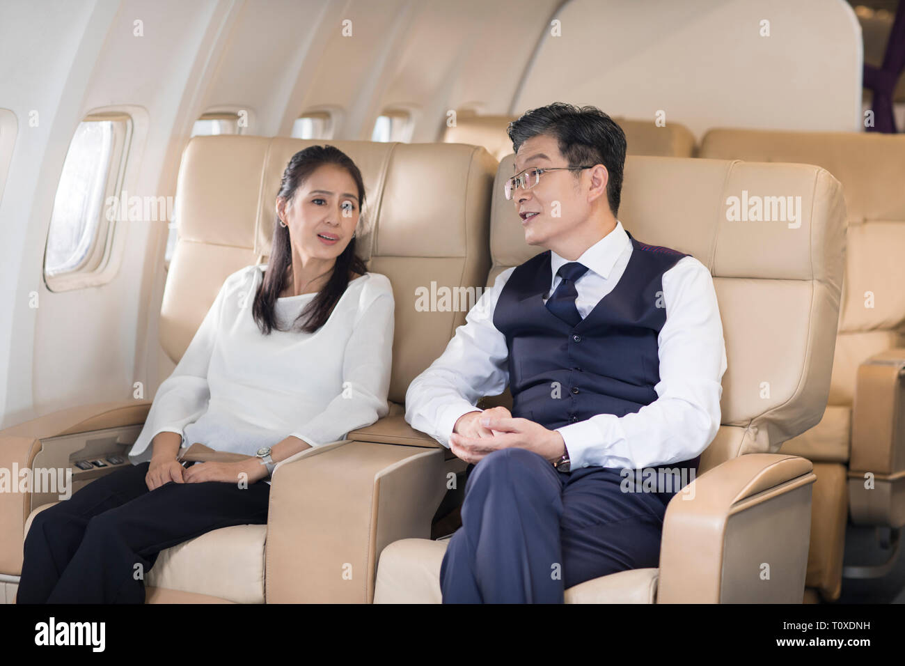 Business people talking on airplane Stock Photo - Alamy