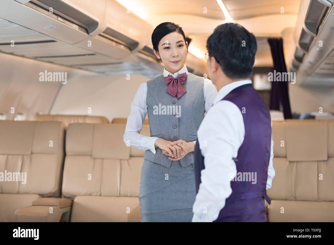 Airline stewardess talking with passenger on airplane Stock Photo - Alamy