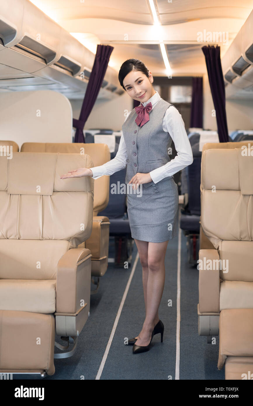 Smiling airline stewardess greeting on airplane Stock Photo - Alamy