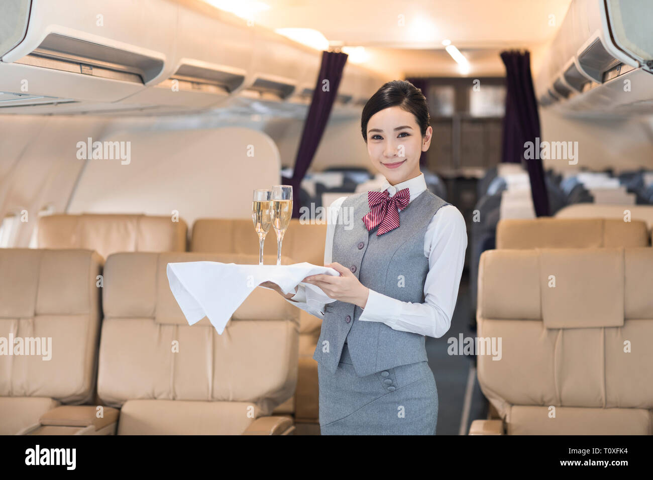 Smiling airline stewardess serving champagne on airplane Stock Photo ...