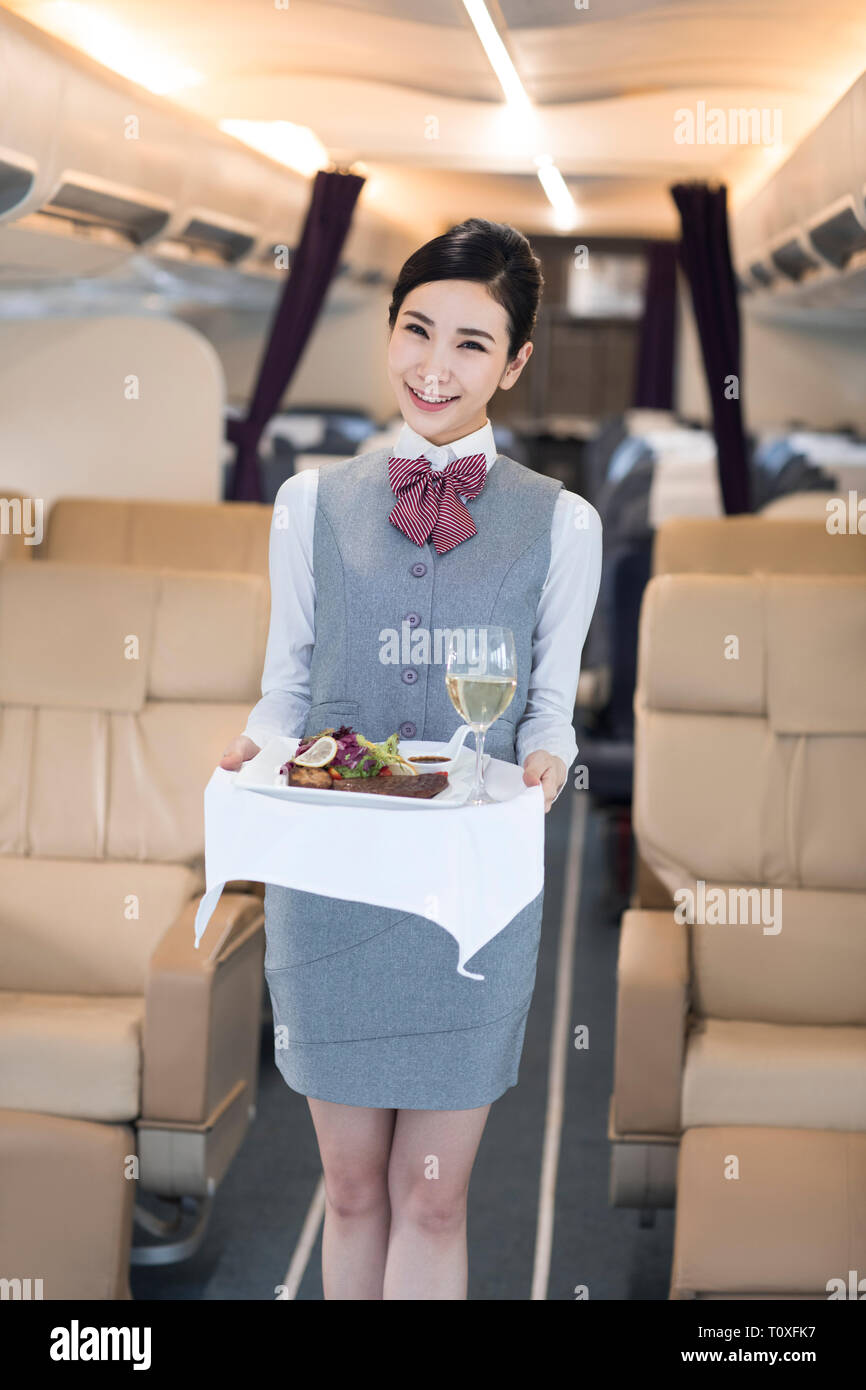 Smiling airline stewardess serving food in first class Stock Photo - Alamy