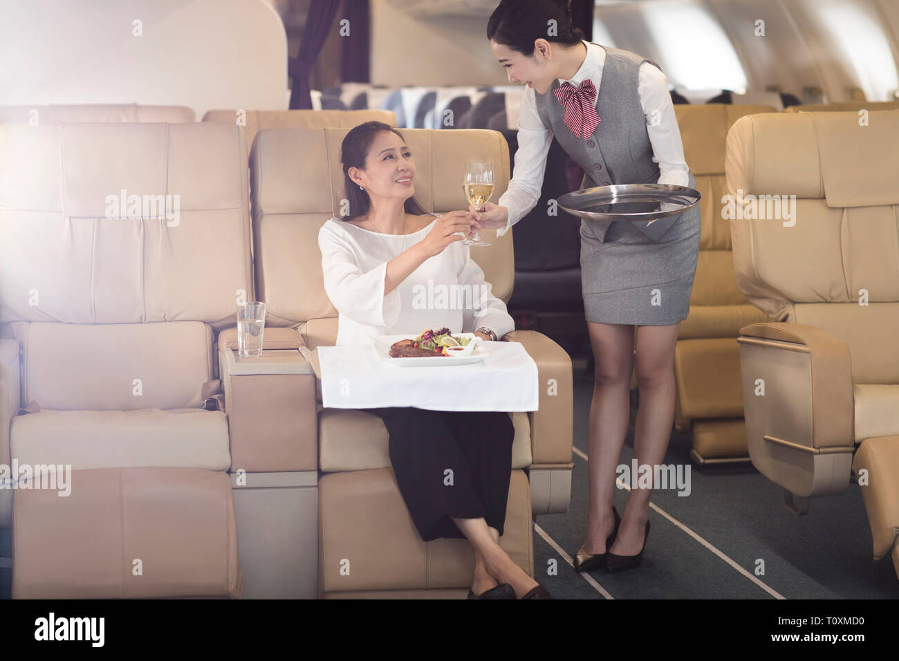Airline stewardess serving food to passenger Stock Photo - Alamy