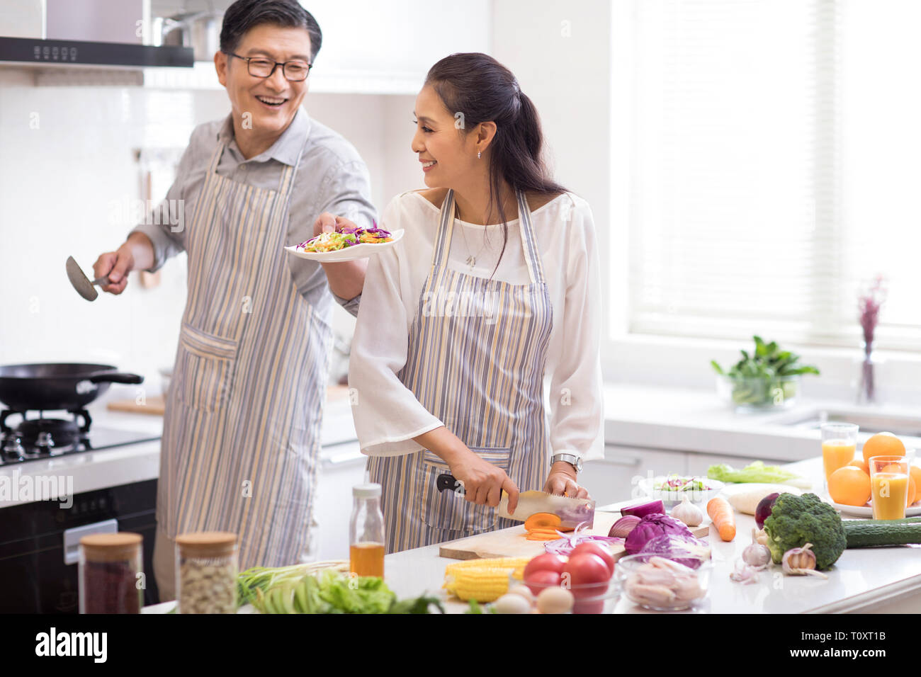 Happy mature couple cooking in kitchen Stock Photo - Alamy