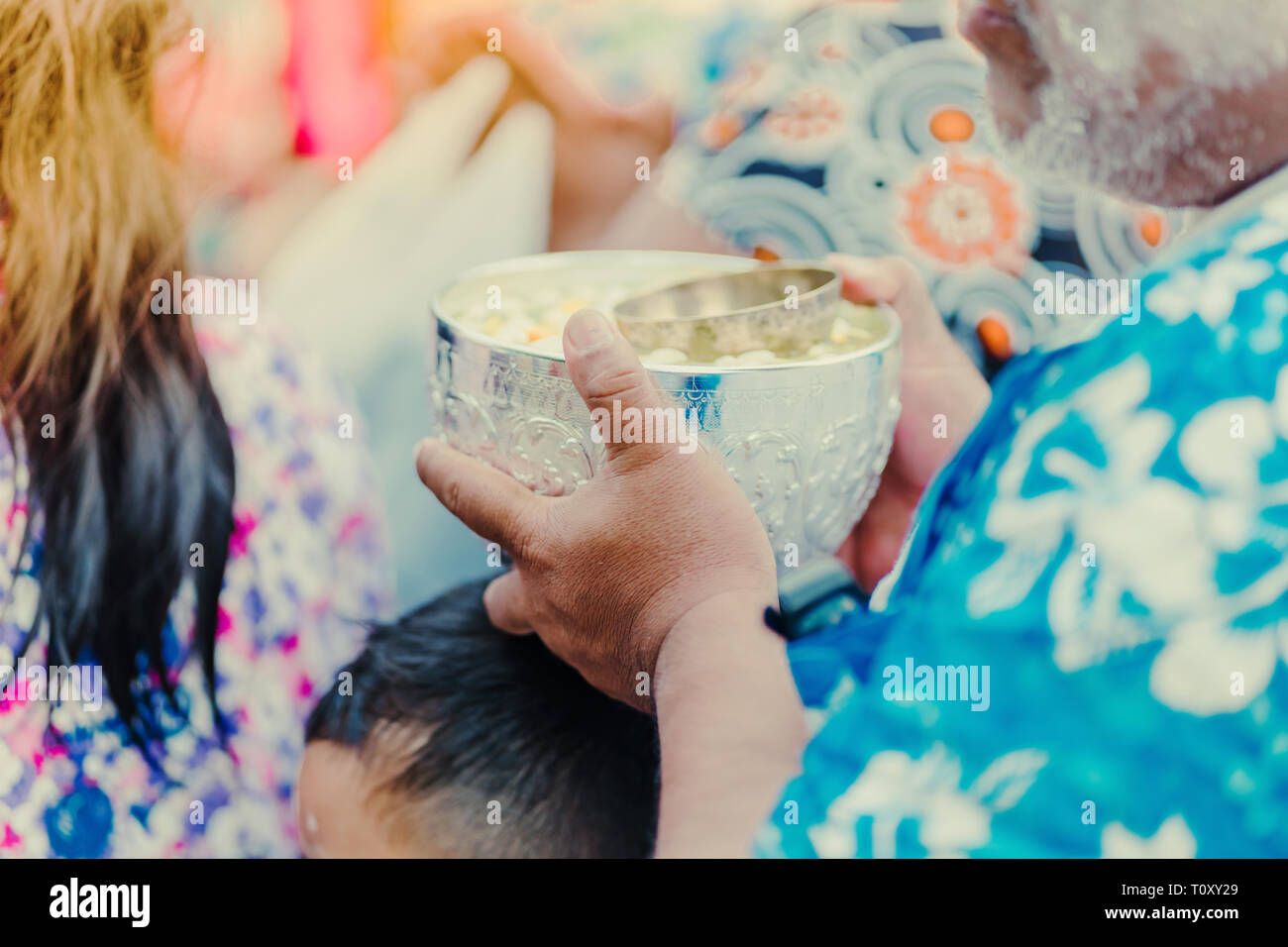 People are holding a bowl of water perfume with flower preparing to ...