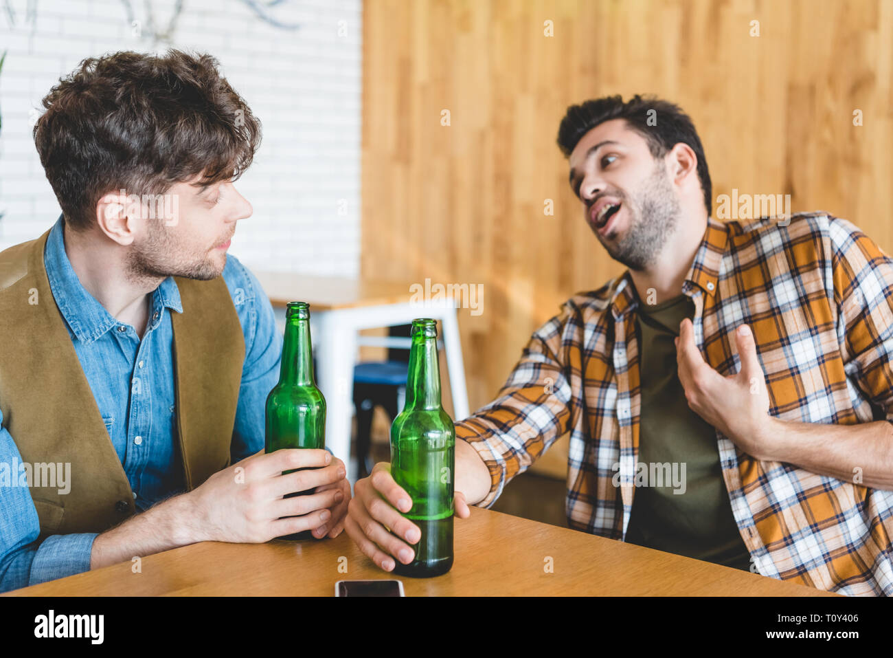 handsome men holding glass bottles of beer and talking at cafe Stock ...