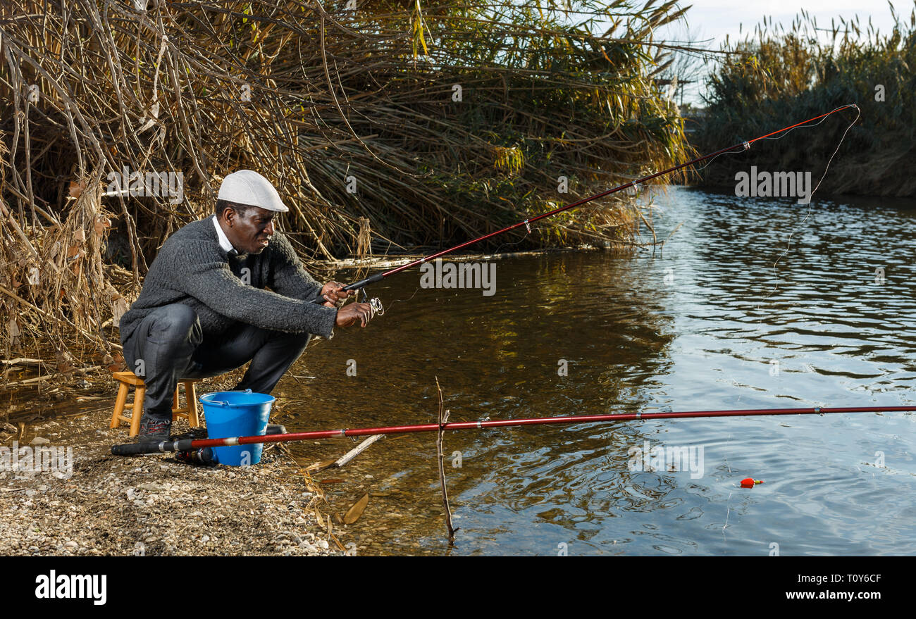 Portrait of friendly African man fishing with rods on river Stock Photo ...