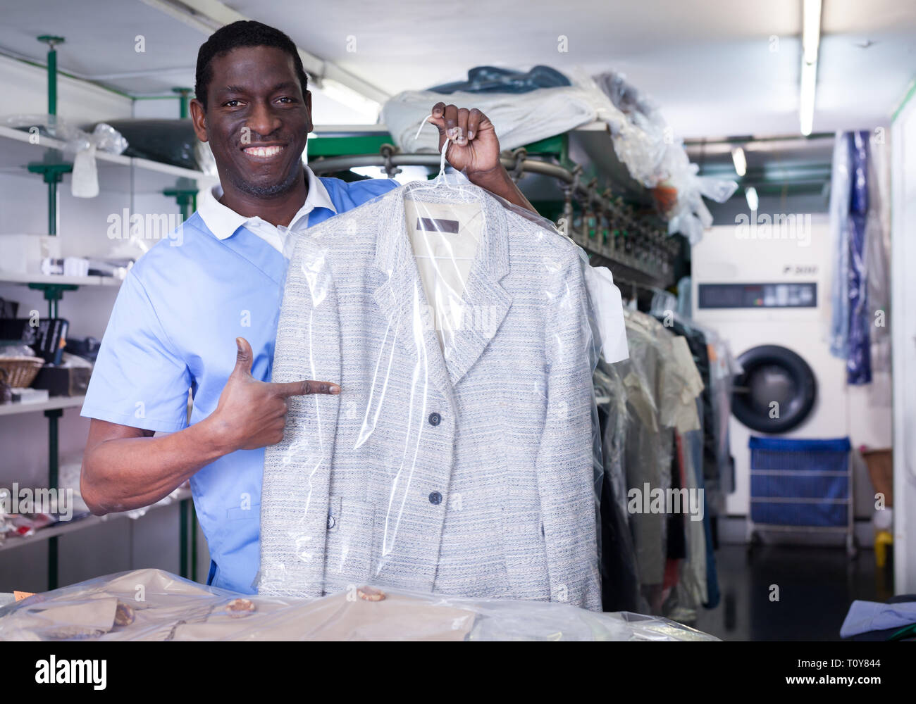 Smiling African-American man administrator of laundry holding clean ...