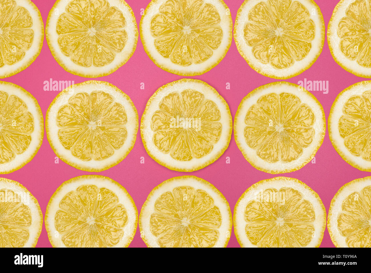Pattern made from fresh lemon slices on a pink background, overhead view, flatlay. Fruit ...