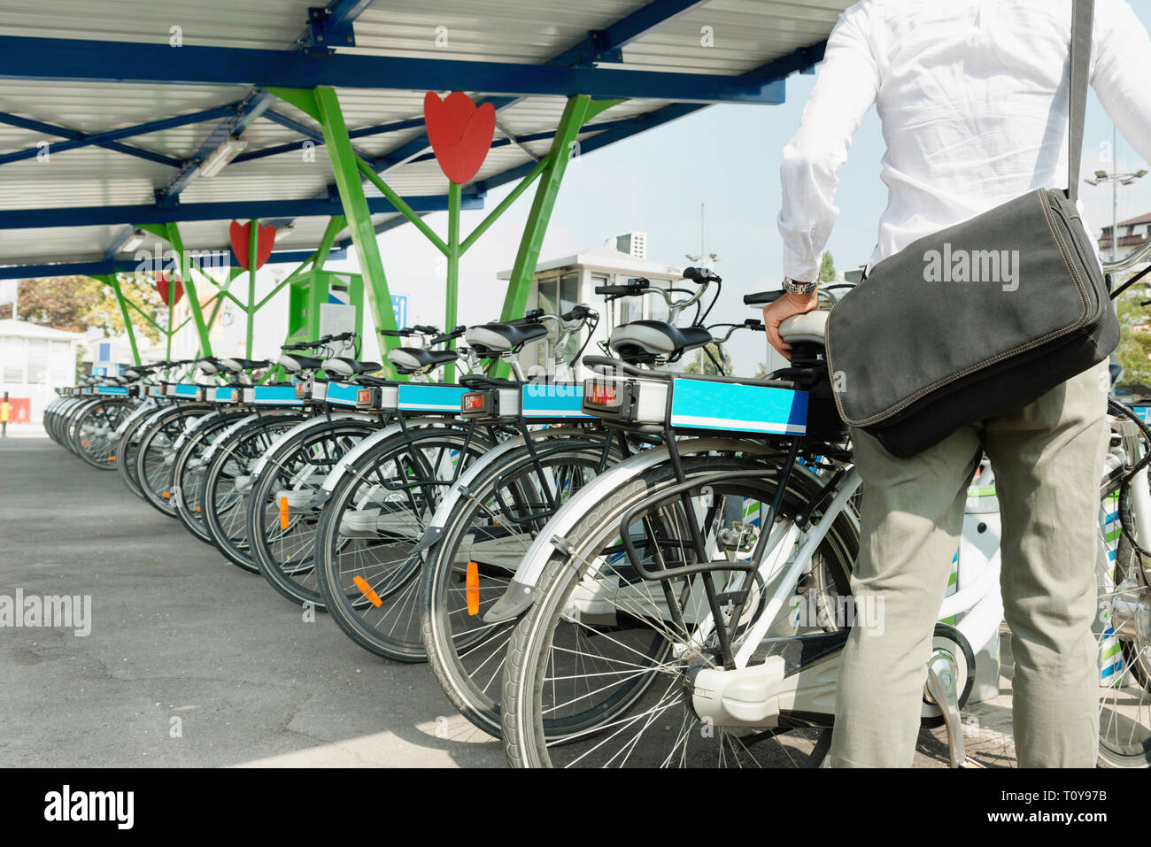 Office worker takes e-bike from bicycle sharing system station Stock ...
