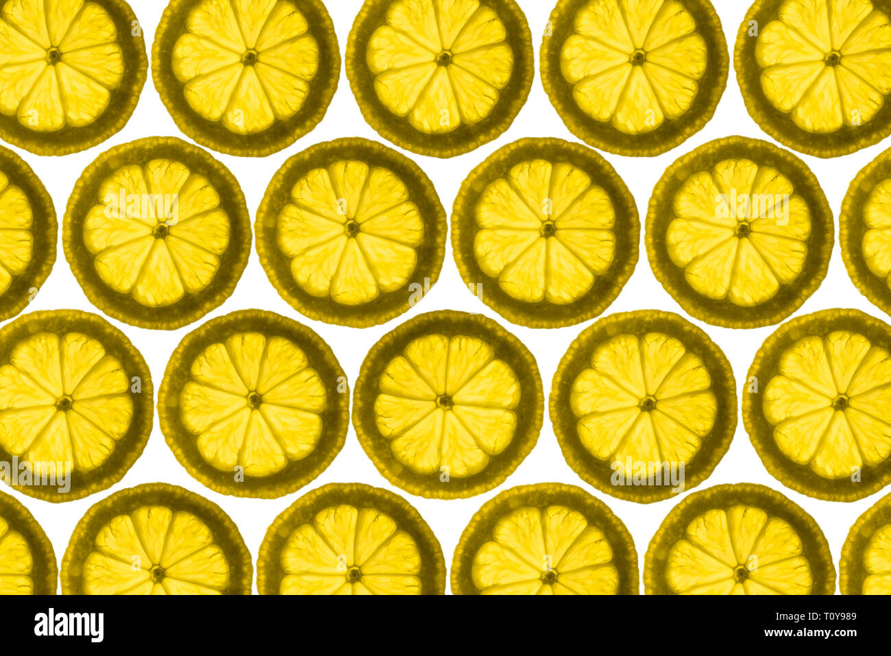 Pattern made of lemon slices illuminated with light from the bottom on a white background ...