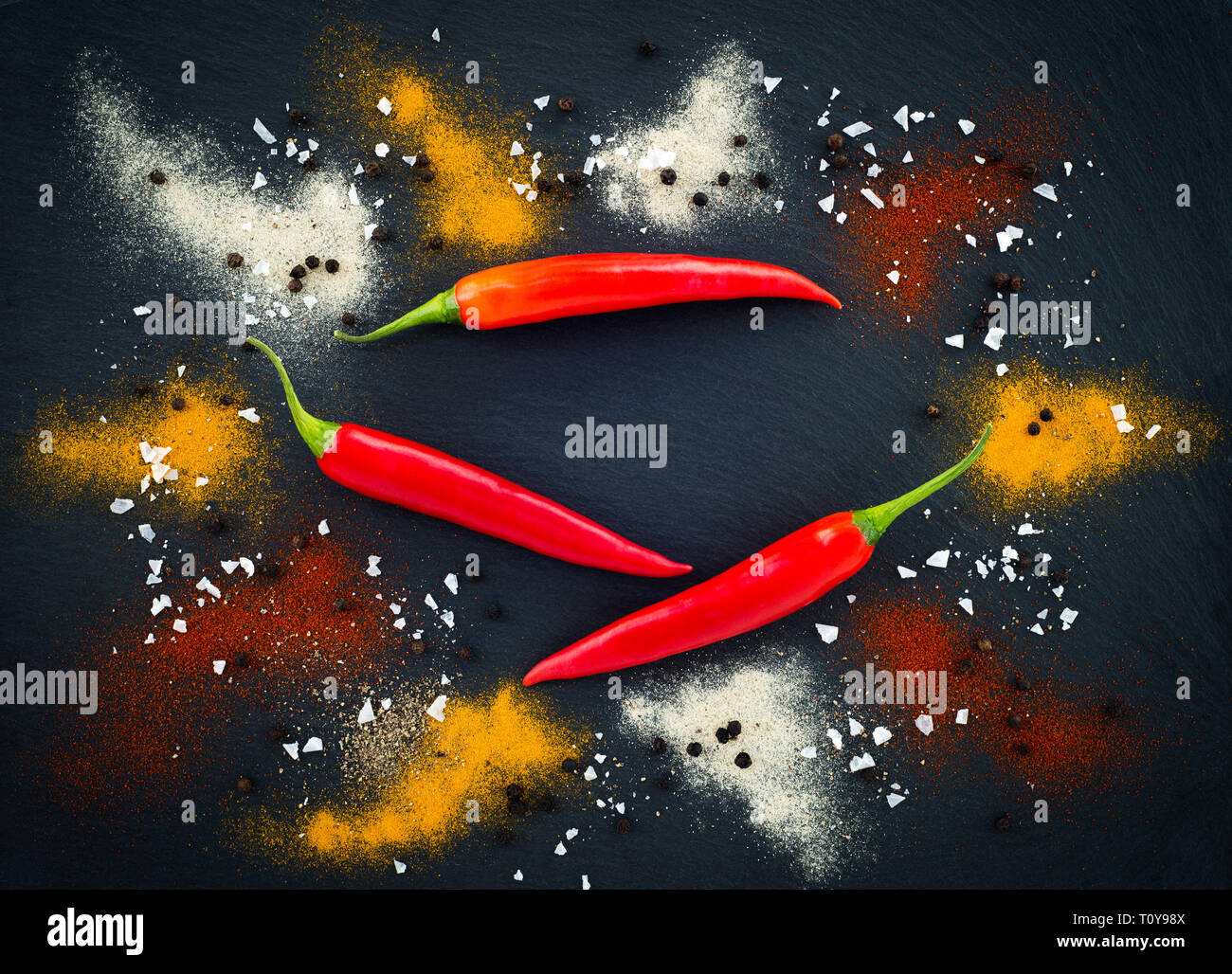 Salt and pepper seasoning on dark slate background. Red chili peppers ...