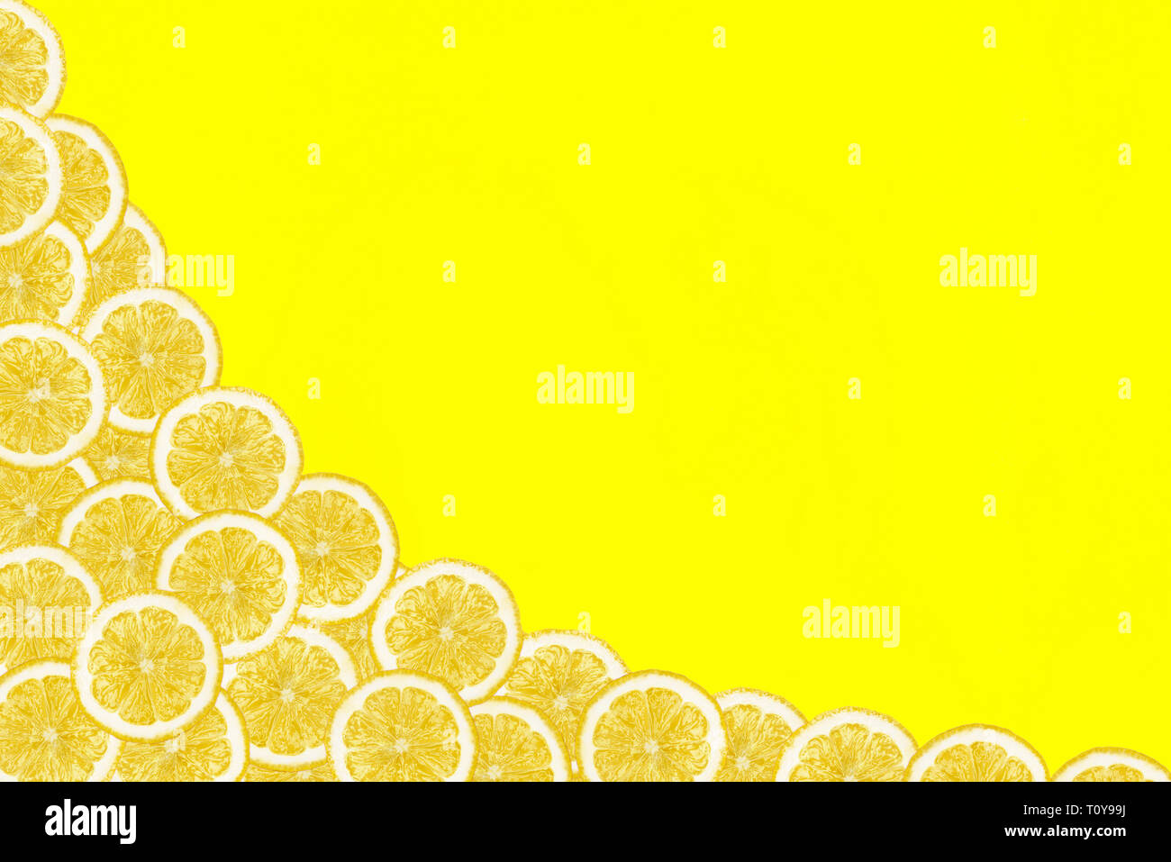 Pattern made from fresh lemon slices on a yellow background with copy space on the right ...