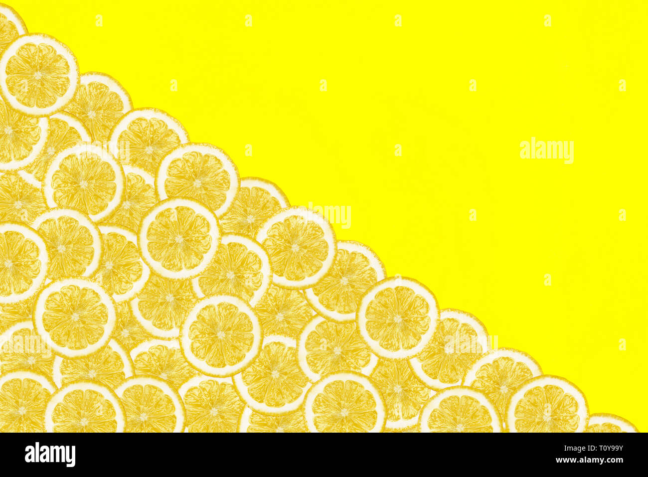 Pattern made from fresh lemon slices on a yellow background with copy space on the right ...