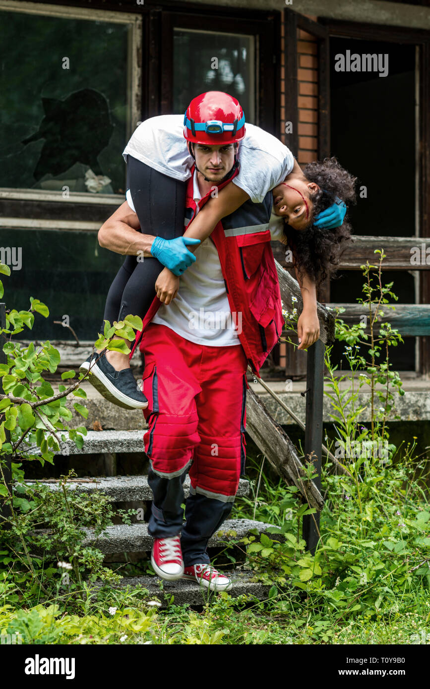 Rescue worker evacuating woman from house Stock Photo - Alamy