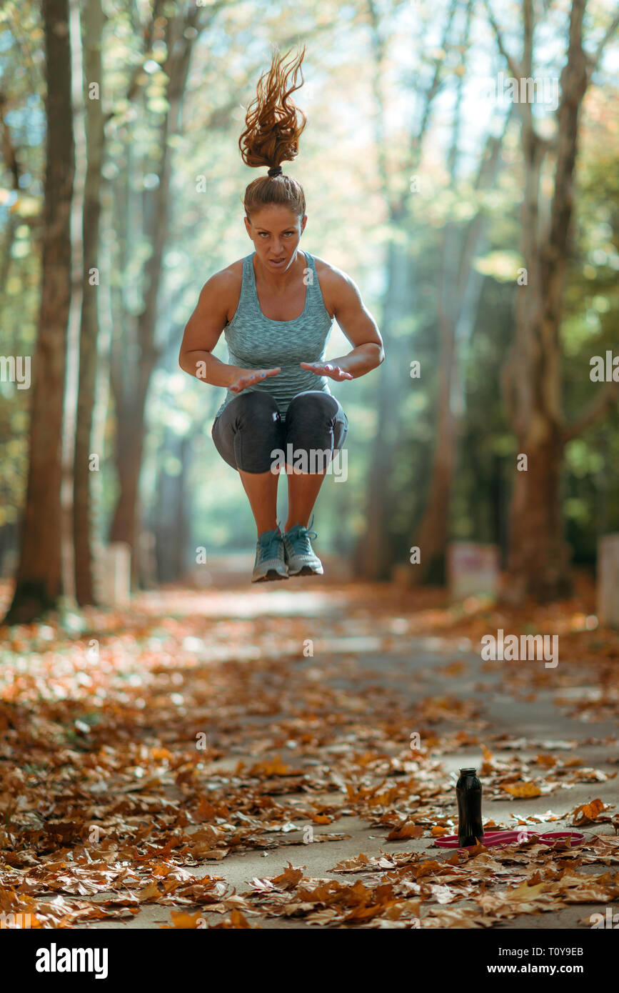 Woman exercising outdoors, in public park. Doing high jump Stock Photo ...