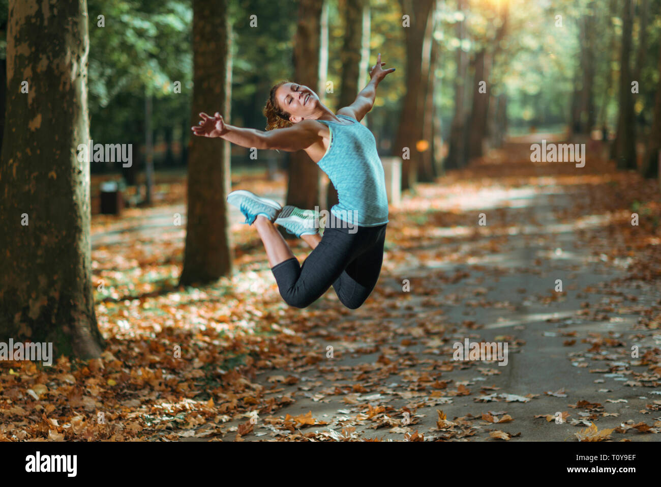 Woman doing star jump outdoors, in public park Stock Photo - Alamy