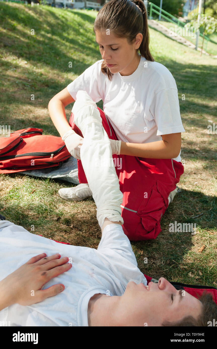 First aid treatment of injured patient, bandaging arm by young female ...