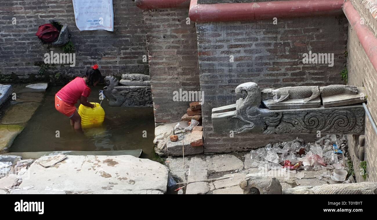 Kathmandu. 22nd Mar, 2019. A kid fills water from the traditional stone ...