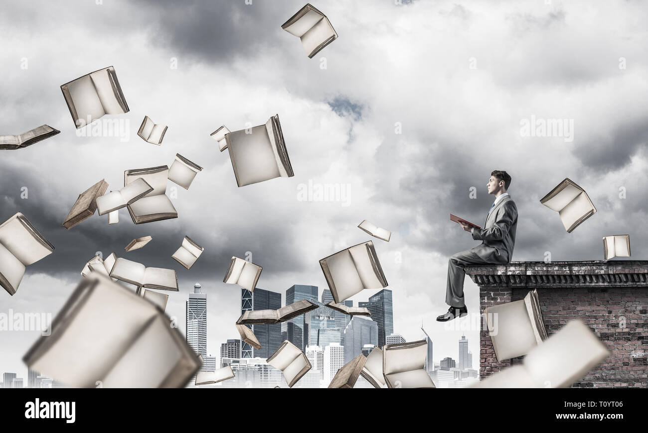 Man on roof reading book and many of them flying in air Stock Photo - Alamy