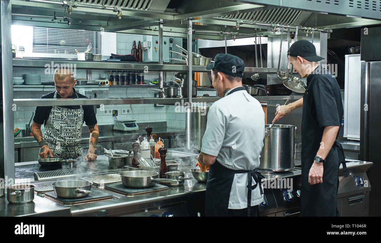 Cooking process. Professional team of chef and two young assistant ...