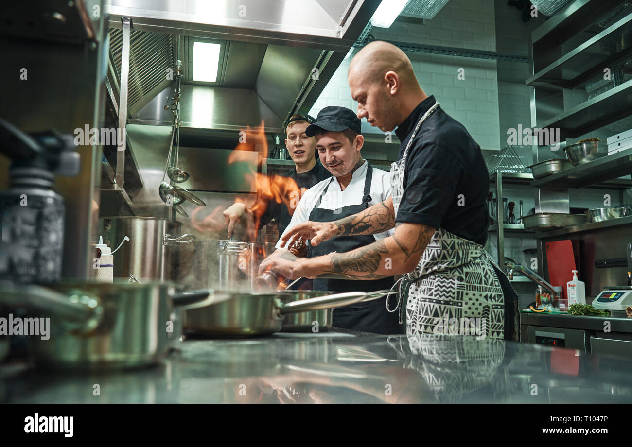 Extreme cooking. Profesional chef teaching his two young trainees how ...