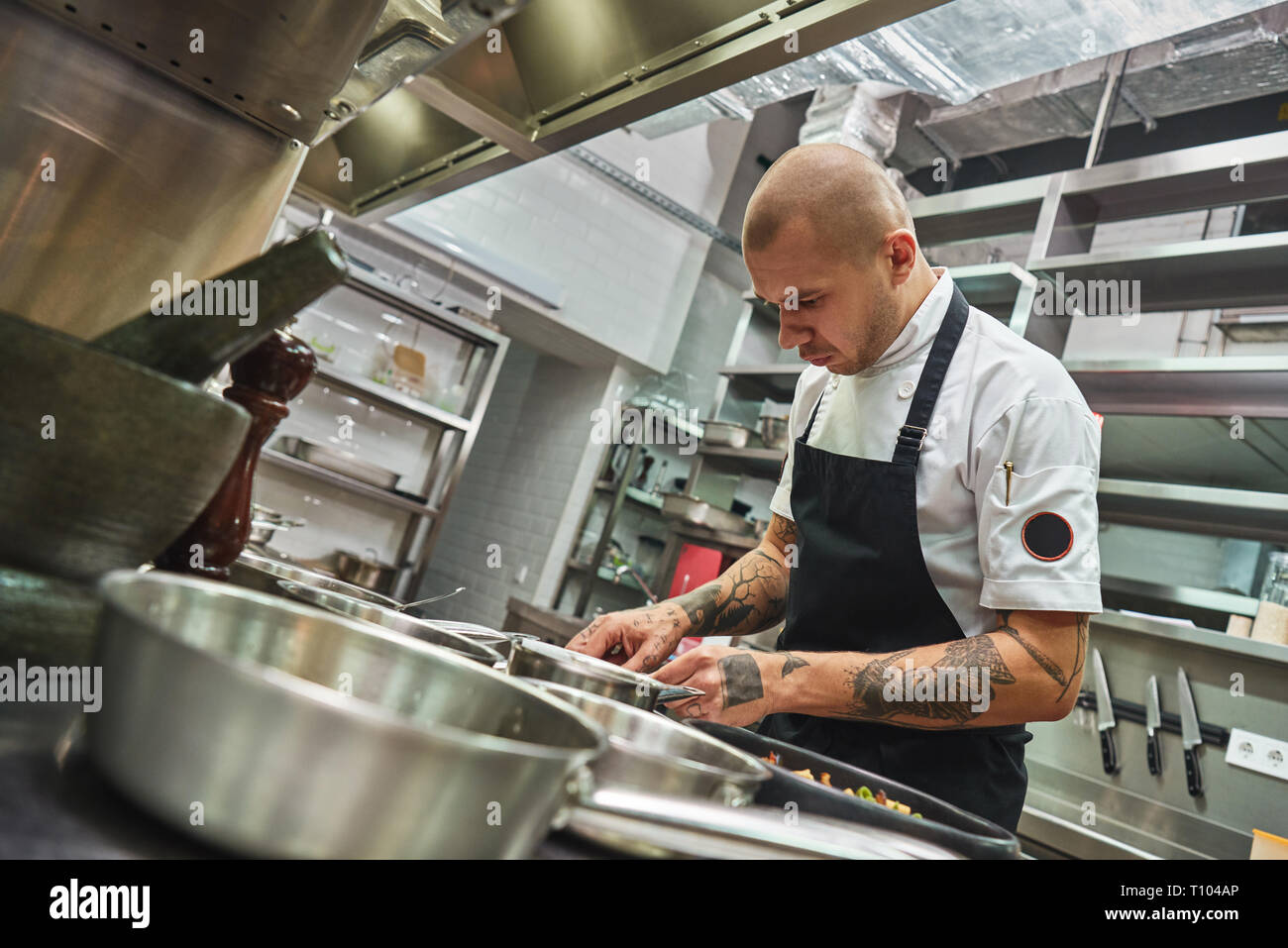 Inspiration in cooking. Young male chef with several tattoos on his ...